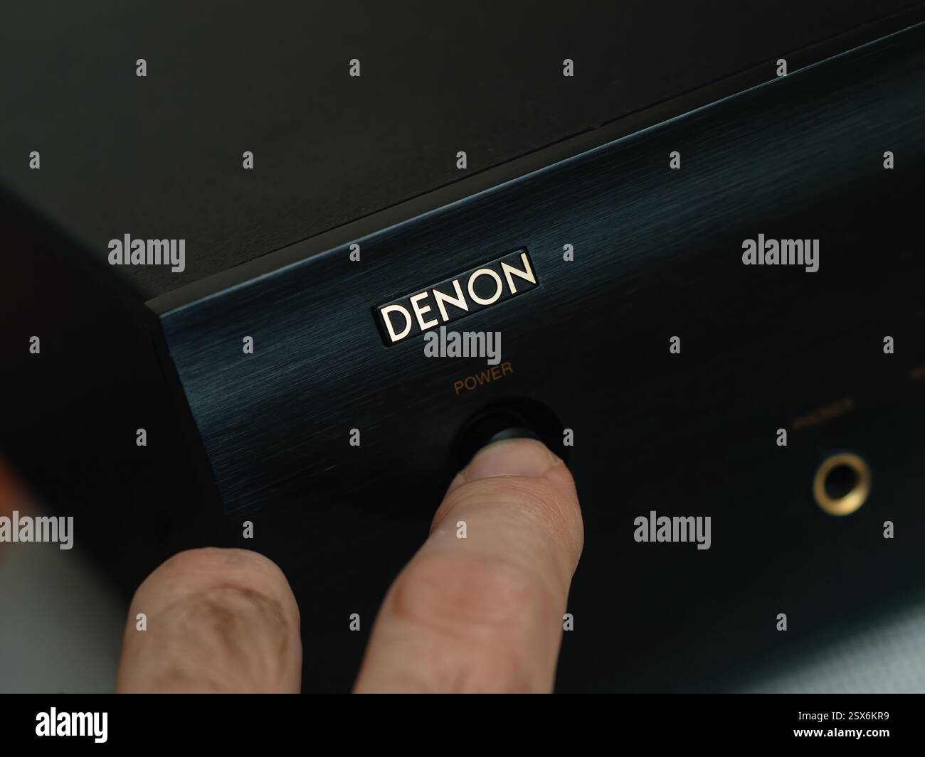 Paris, France - May 28, 2023: A close-up of a finger pressing the power button on a Denon SACD ...
