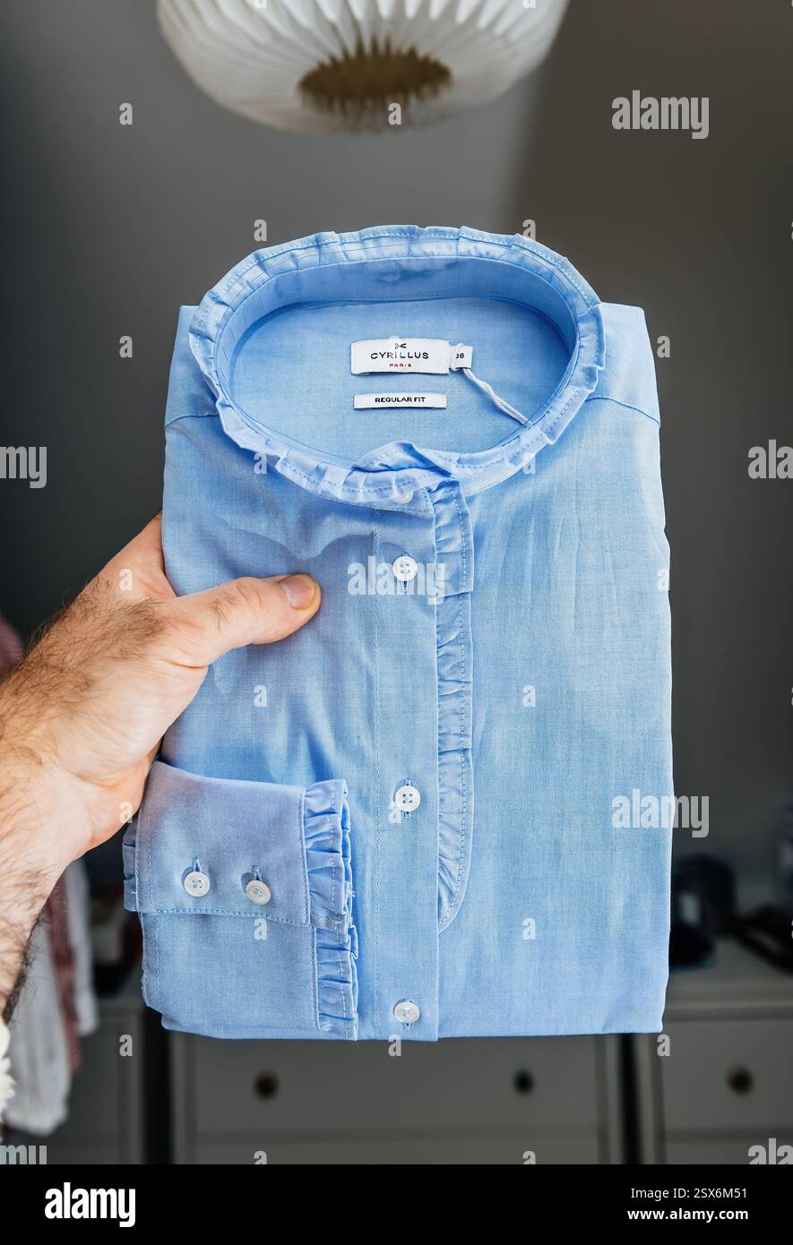 Paris, France - Feb 13, 2025: A person holds a neatly folded light blue ...