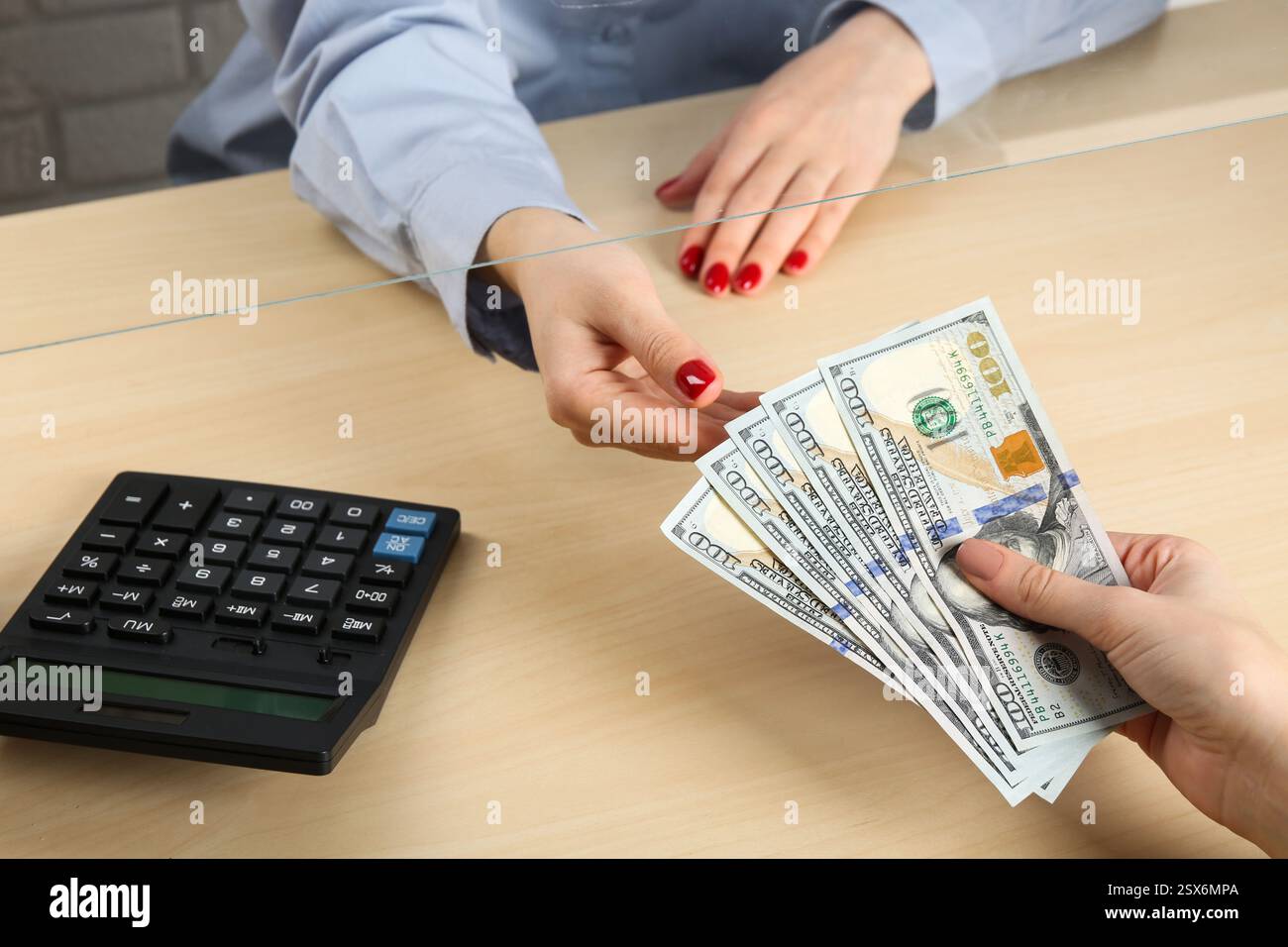 Client giving dollar banknotes to cashier at table in money exchange ...