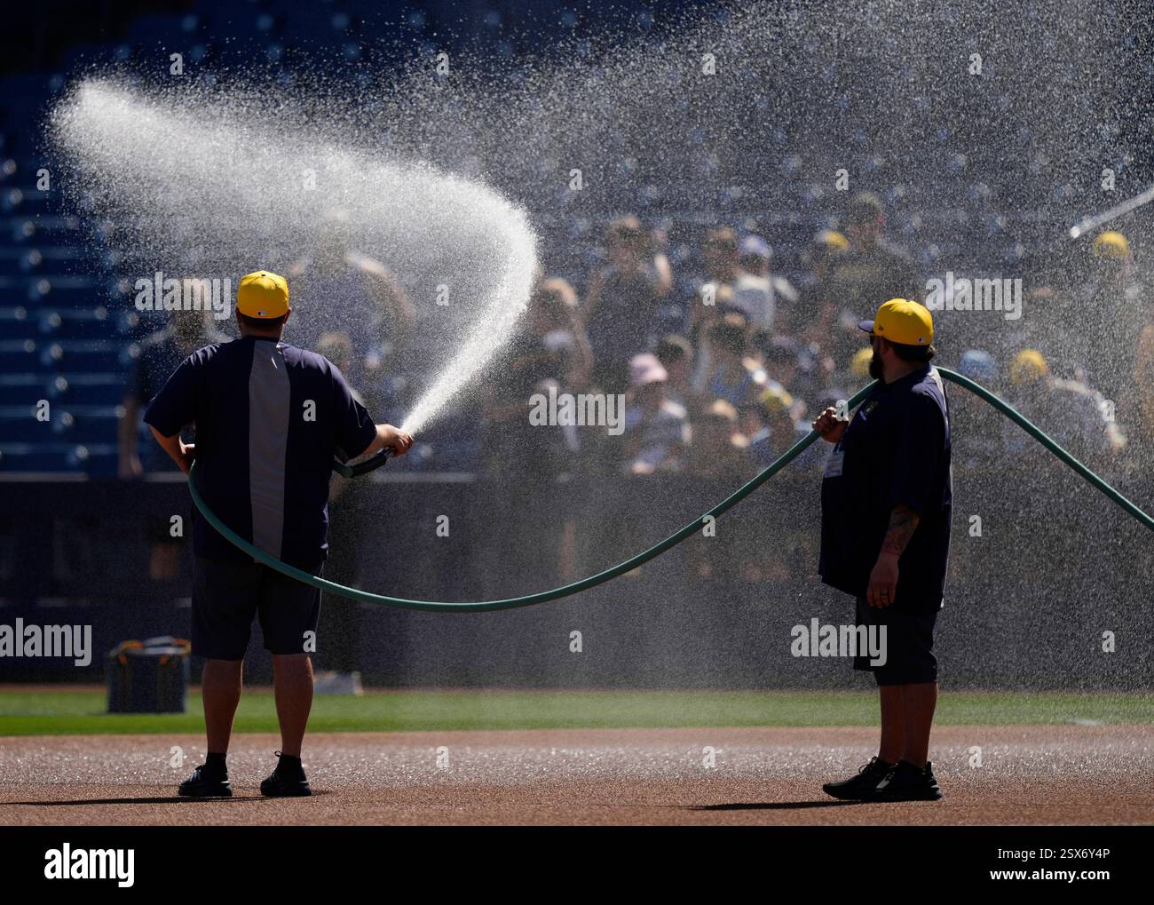 Members of the grounds crew wet the field before a spring training ...