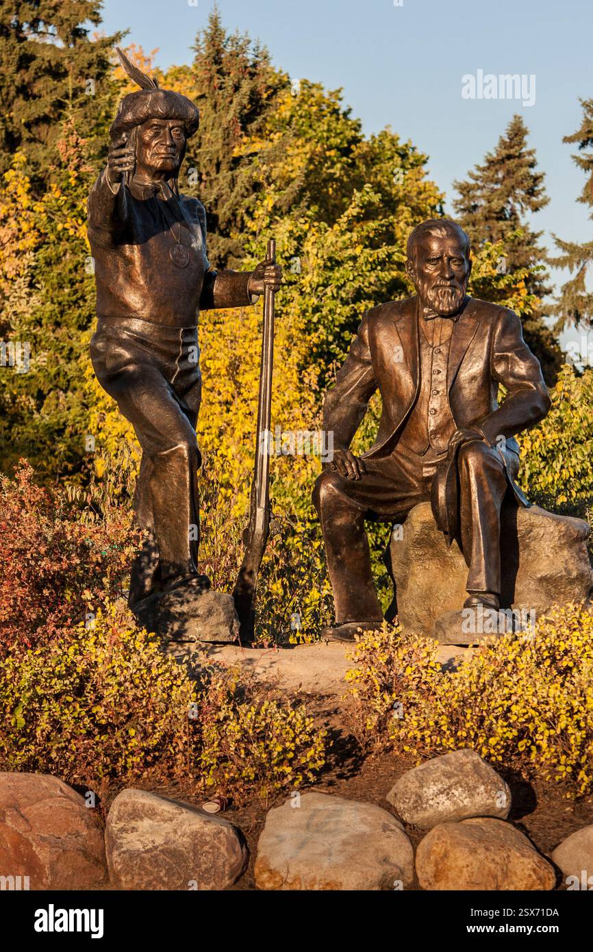 Two statues of men sitting on a rock, one of them pointing to the other ...