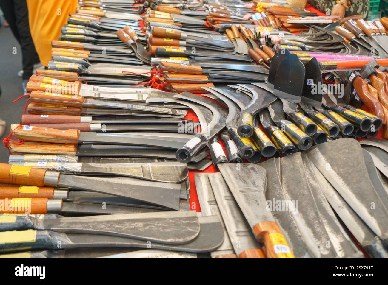 close-up shot of various knives, machetes, and gardening tools arranged ...