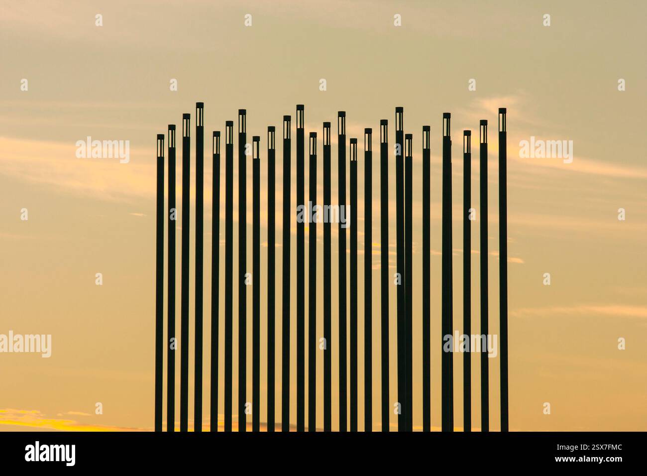 Tall structure with many poles is silhouetted against a cloudy sky. The ...