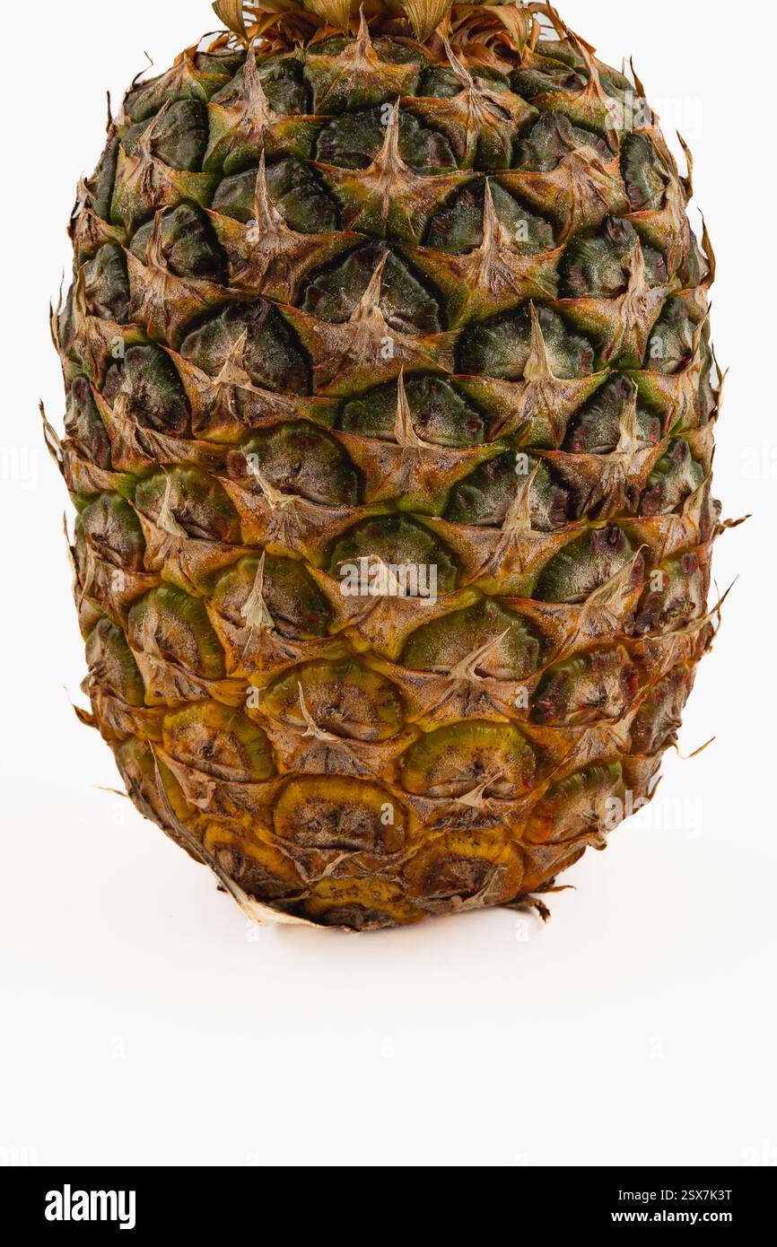 A ripe pineapple stands prominently with its spiky, textured skin. The ...