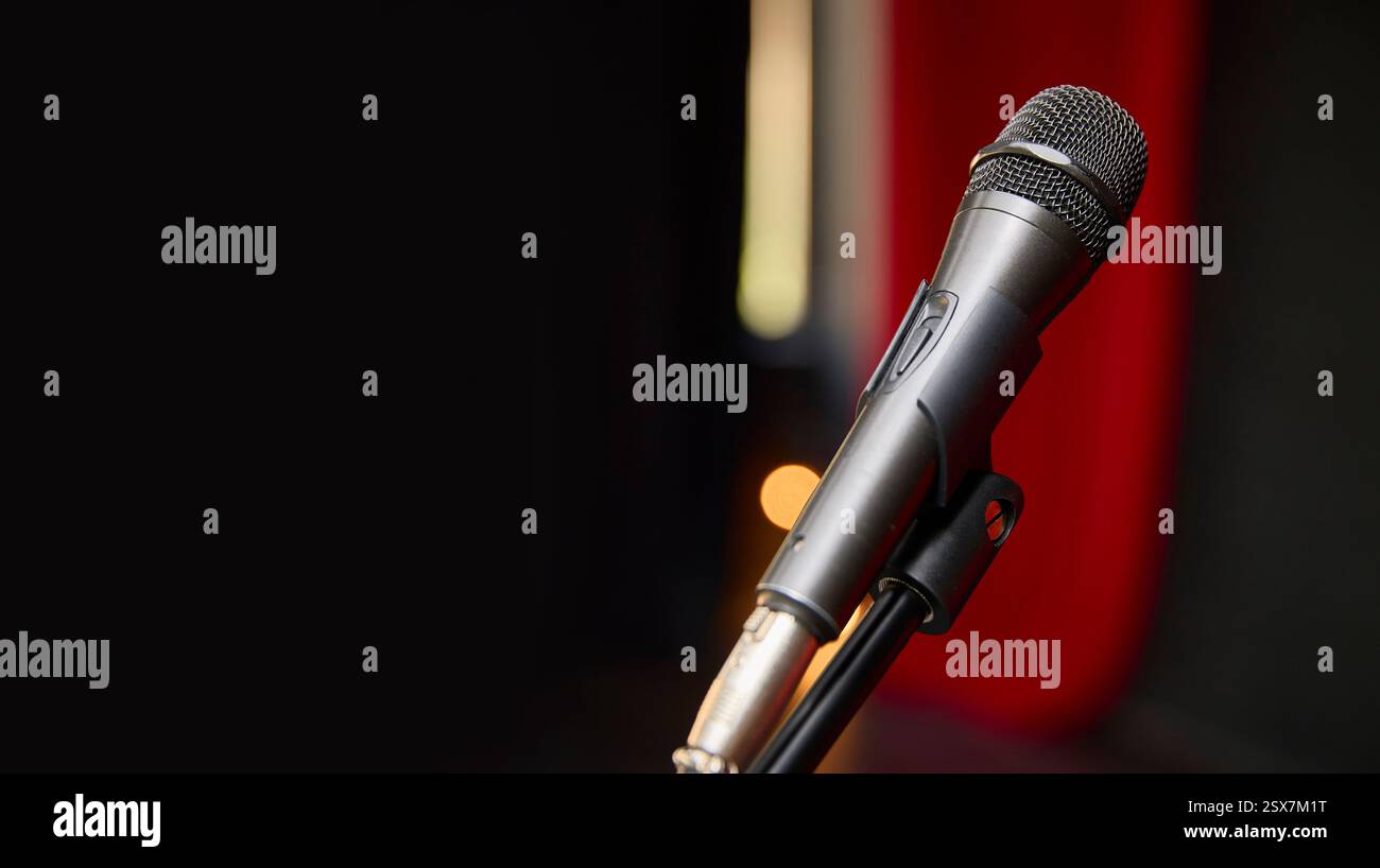 A microphone is positioned on a sturdy stand, located in front of an ...