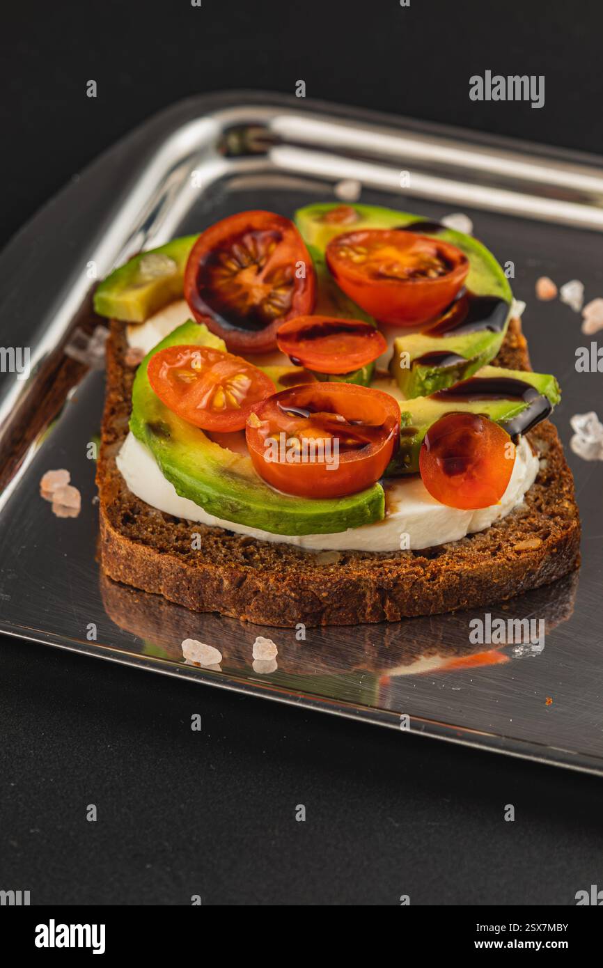 This open-faced sandwich features a thick slice of dark bread topped ...