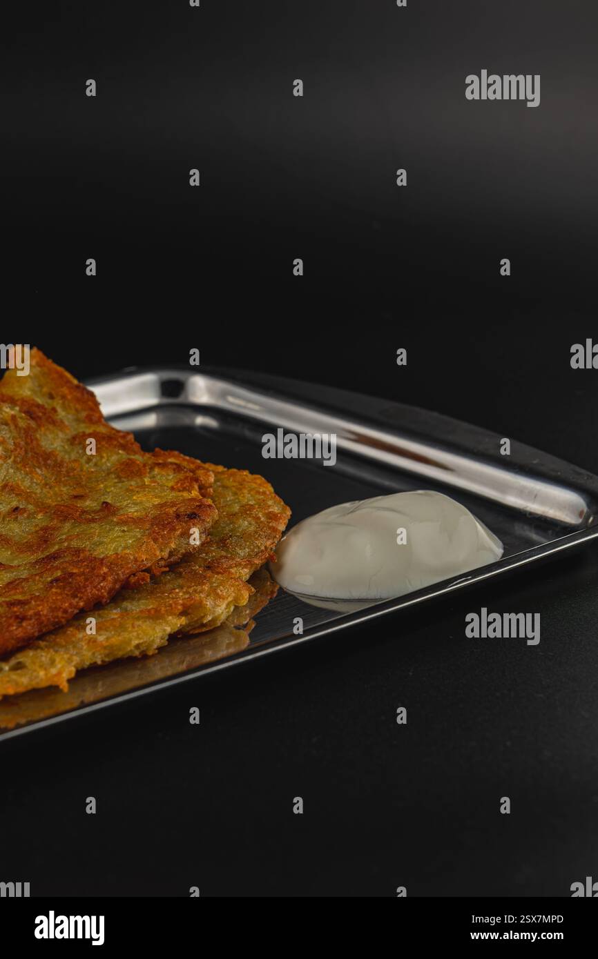 A platter showcases golden-brown, crispy pancakes alongside a smooth ...