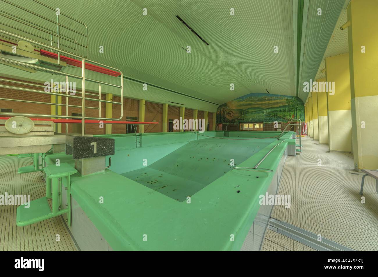 Abandoned indoor swimming pool with diving platform and wall painting ...