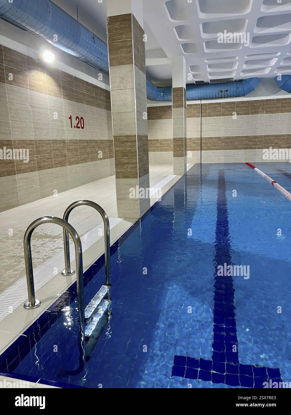 Indoor swimming pool with blue water, surrounding tiles, and supporting ...