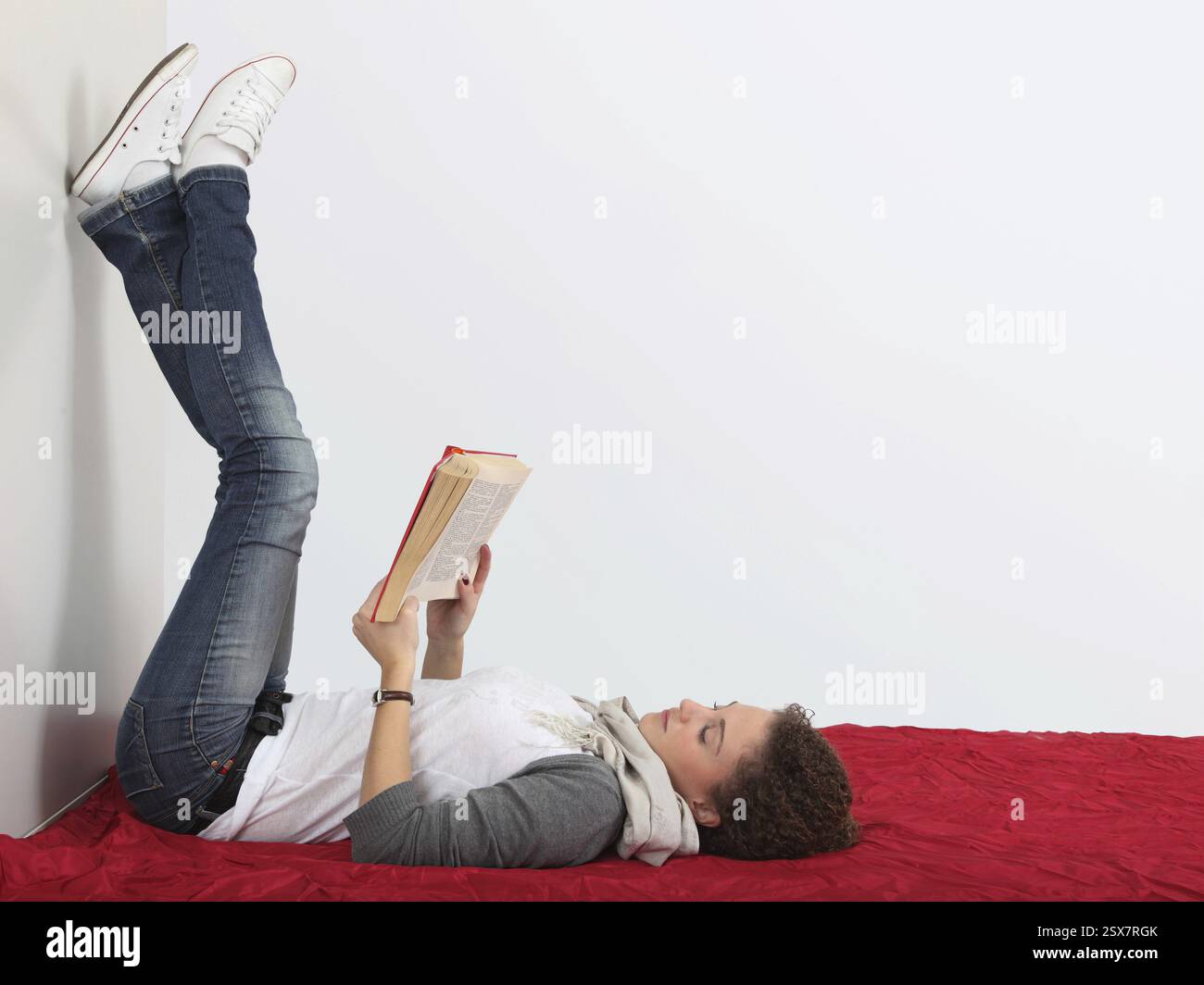 Young woman reading a book in supine position Stock Photo - Alamy