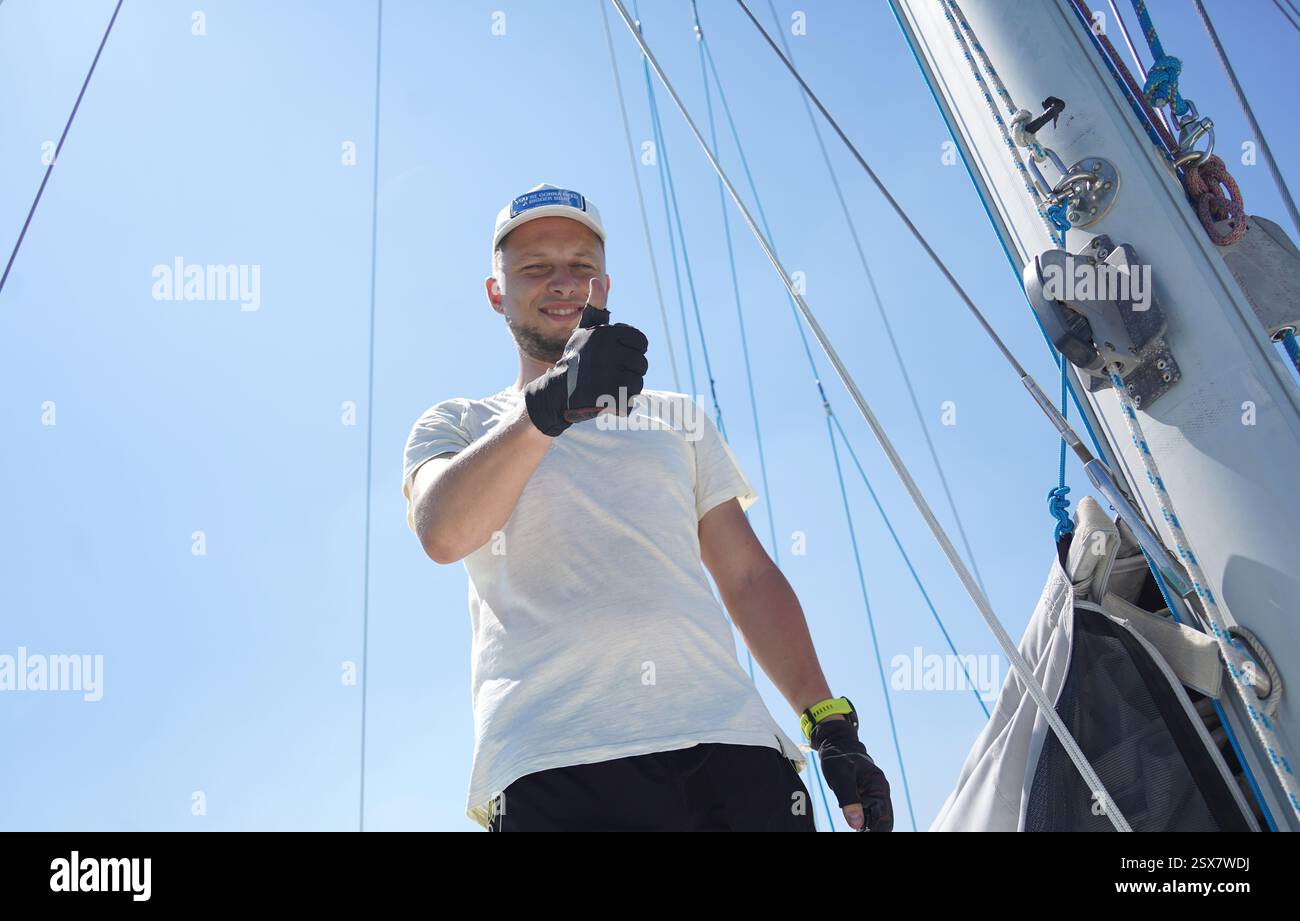 Male captain on deck of sailboat opening sails pulling the rope Stock ...