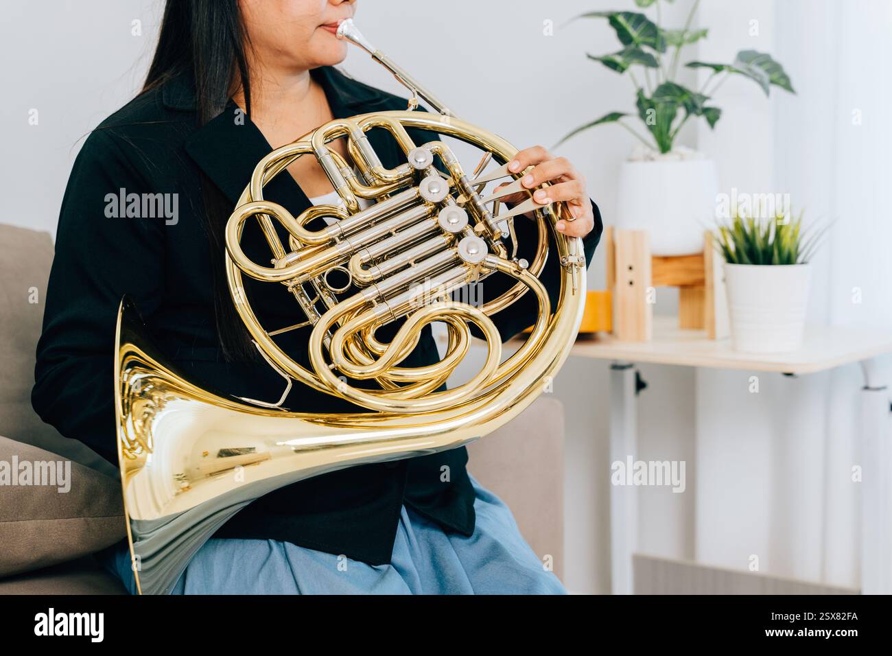 A woman sits on a cozy sofa in her living room, playing a shiny gold ...