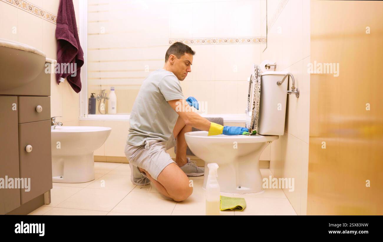 Man cleaning toilet in bathroom with disinfectant and sponge Stock ...
