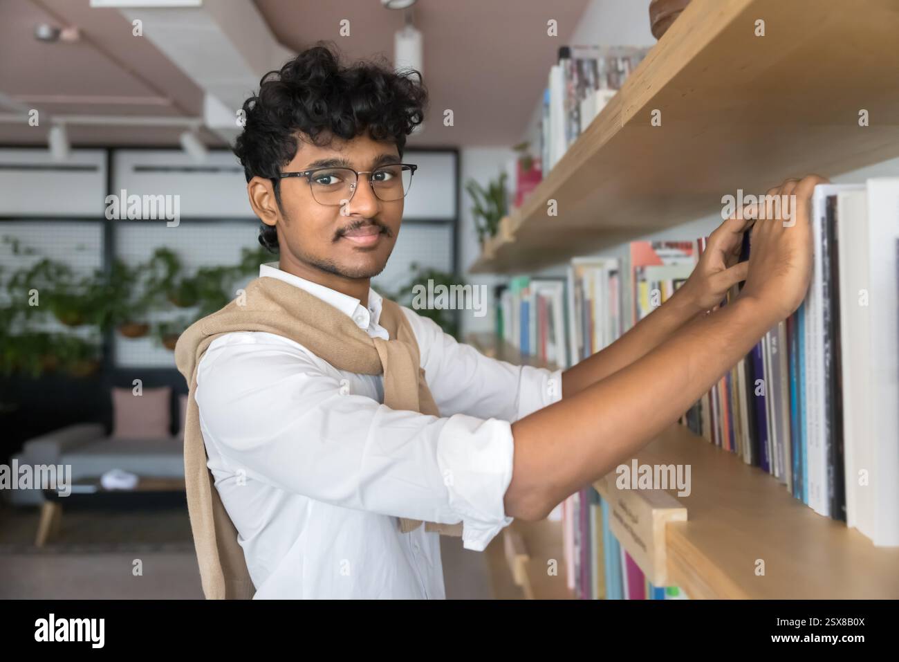 Portrait of Indian guy stands near bookshelves in public library Stock ...