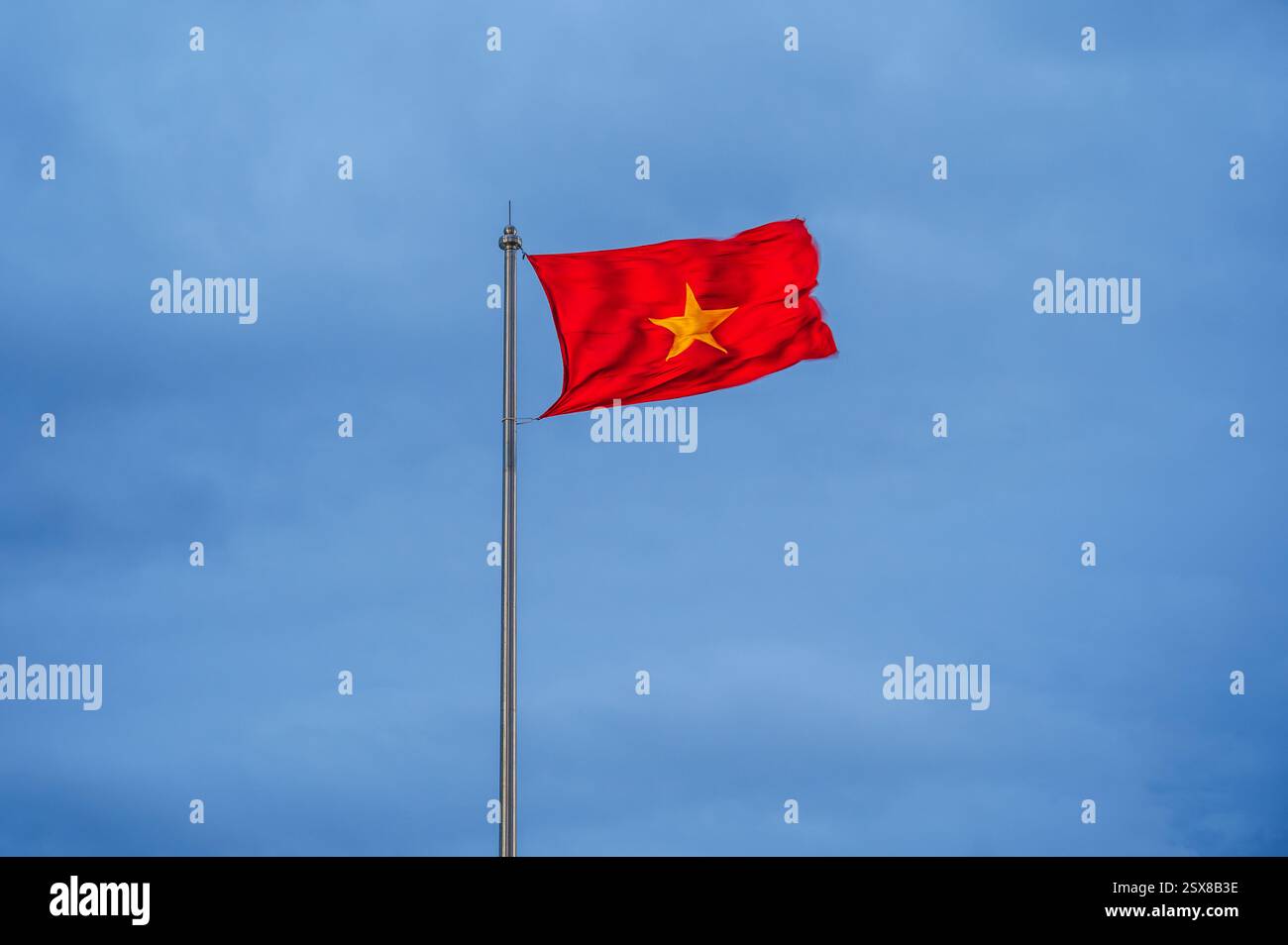 Vietnamese flag waving in the wind with clear blue sky. Yellow star on ...