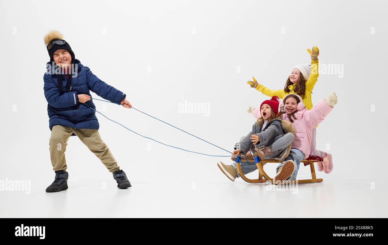 Boy pulling sled with three girls, friends, sitting, all dressed in ...