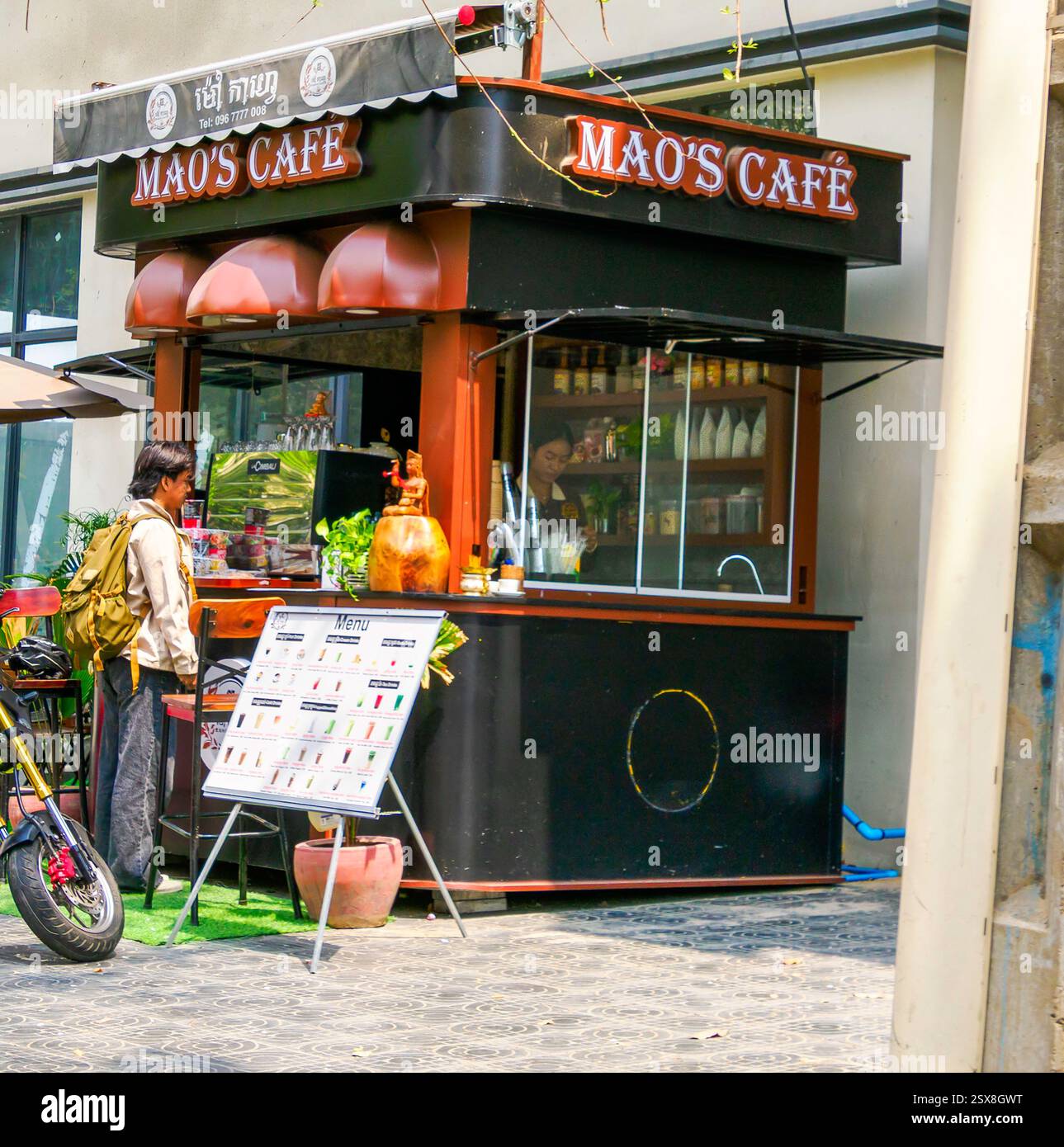 A man buys a drink at a coffee stall in Phnom Penh bearing the name of ...