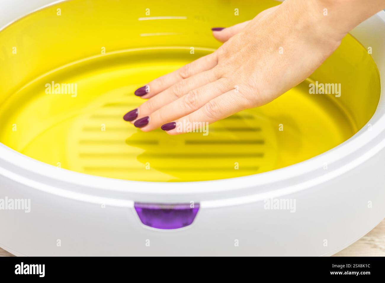 a woman's hand is dipped into melted paraffin. female hand immersed in ...
