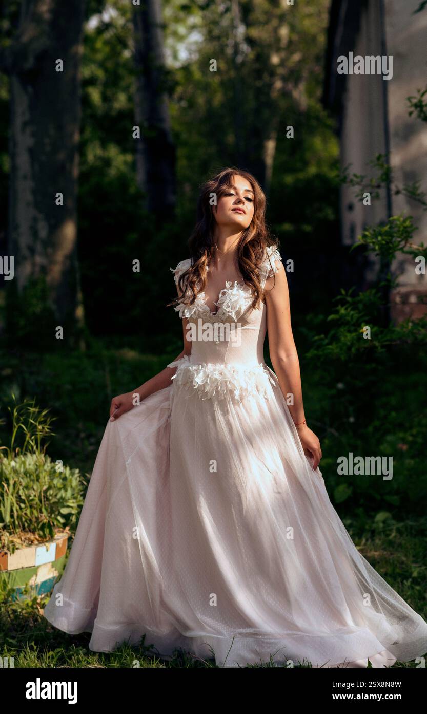 Stunning bride gracefully poses in a spring park, among blossoming ...