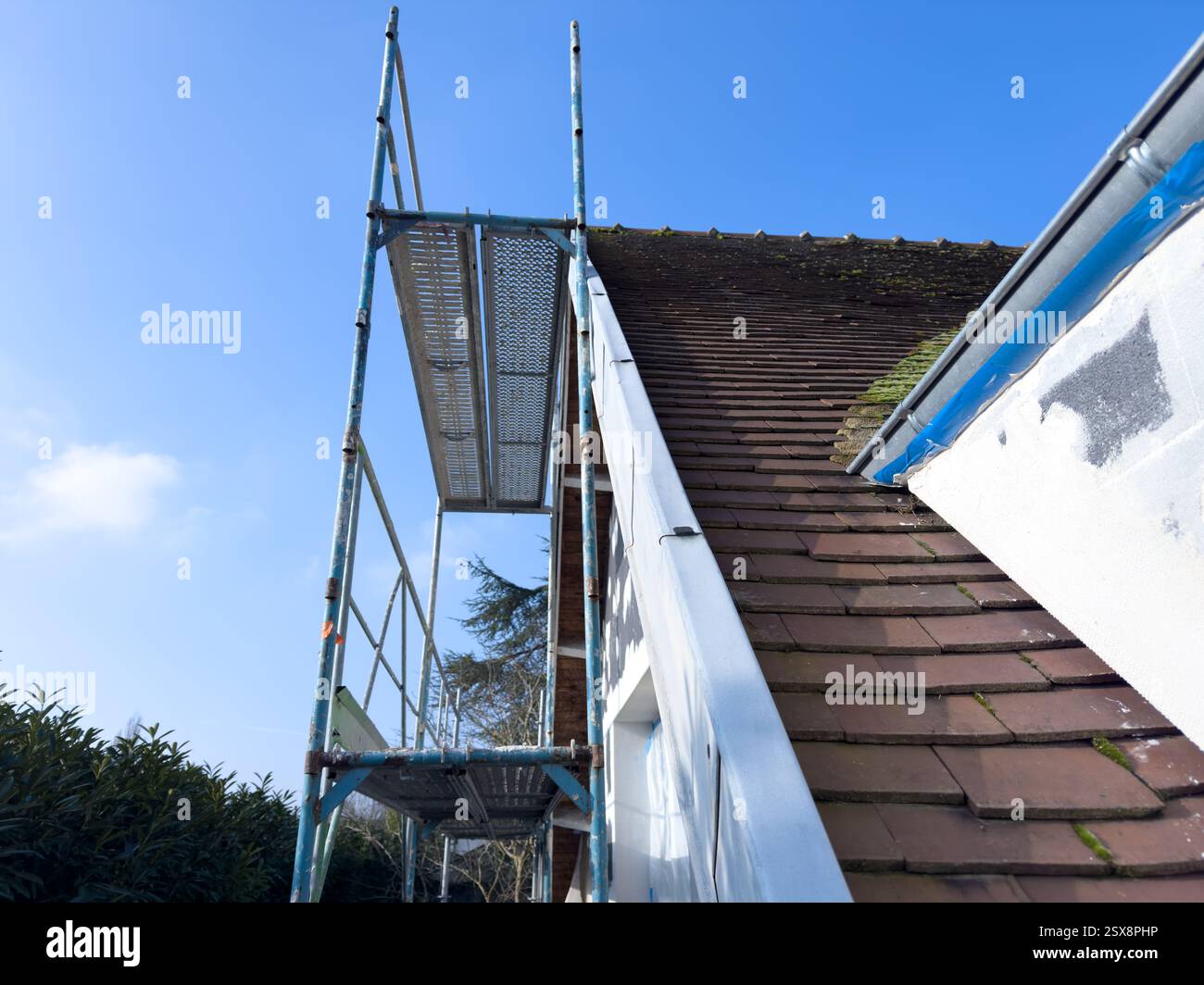 Scaffolding supports a house exterior renovation under a clear blue sky ...