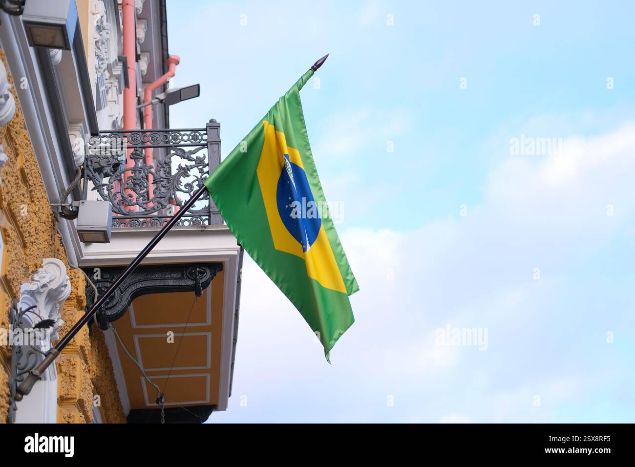 Brazilian flag swaying in wind against blue sky and historical ...