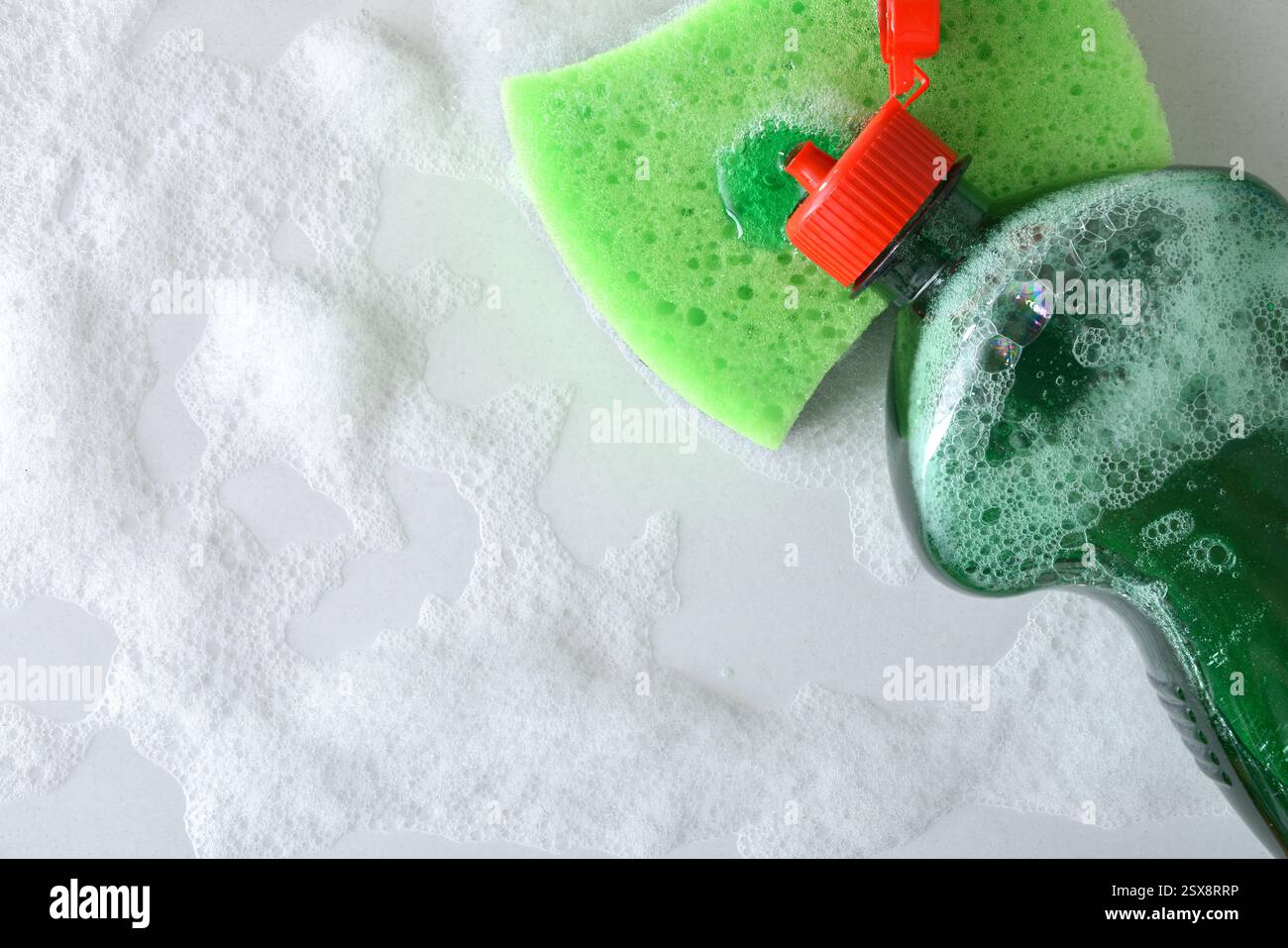 Background with open detergent bottle spilling detergent onto a green ...