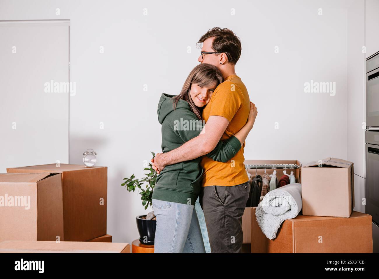 A loving couple shares a warm hug while moving into their new home ...