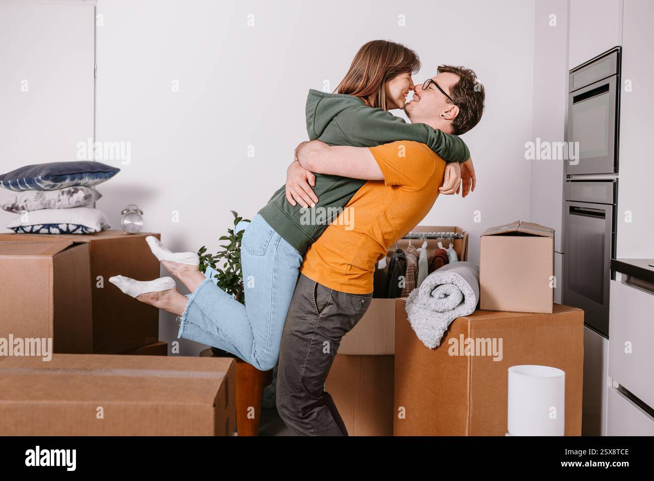 Man lifts woman into the air as they hug and smile, celebrating their ...