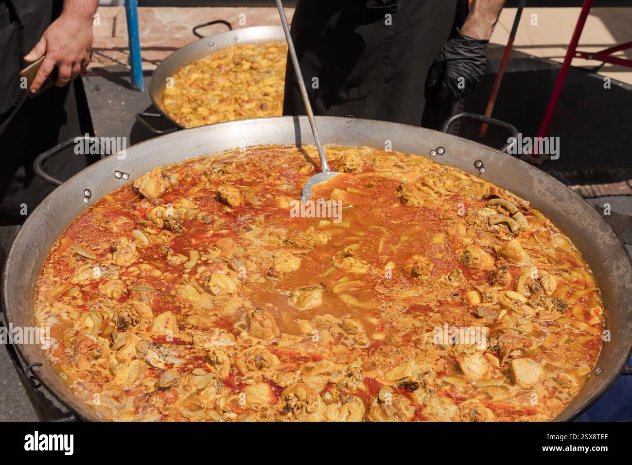 A giant pan of chicken paella, rich with saffron rice, vegetables, and ...