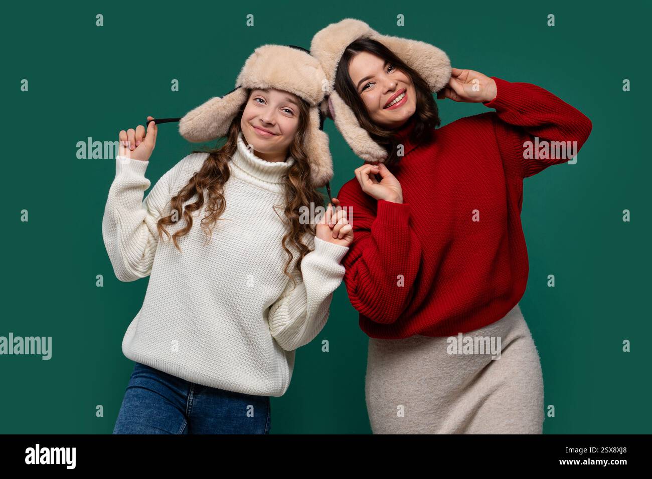 Mum and teenage daughter wear matching furry winter hats, grinning ...