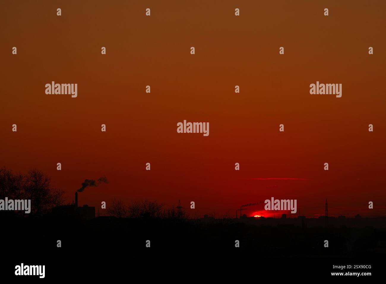 Fiery red sun dipping below horizon with industrial smoke Stock Photo ...