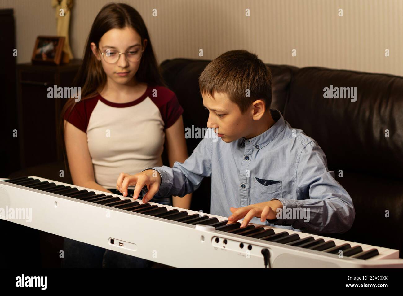 Boy practicing keyboard while girl observes with focus. Practicing ...