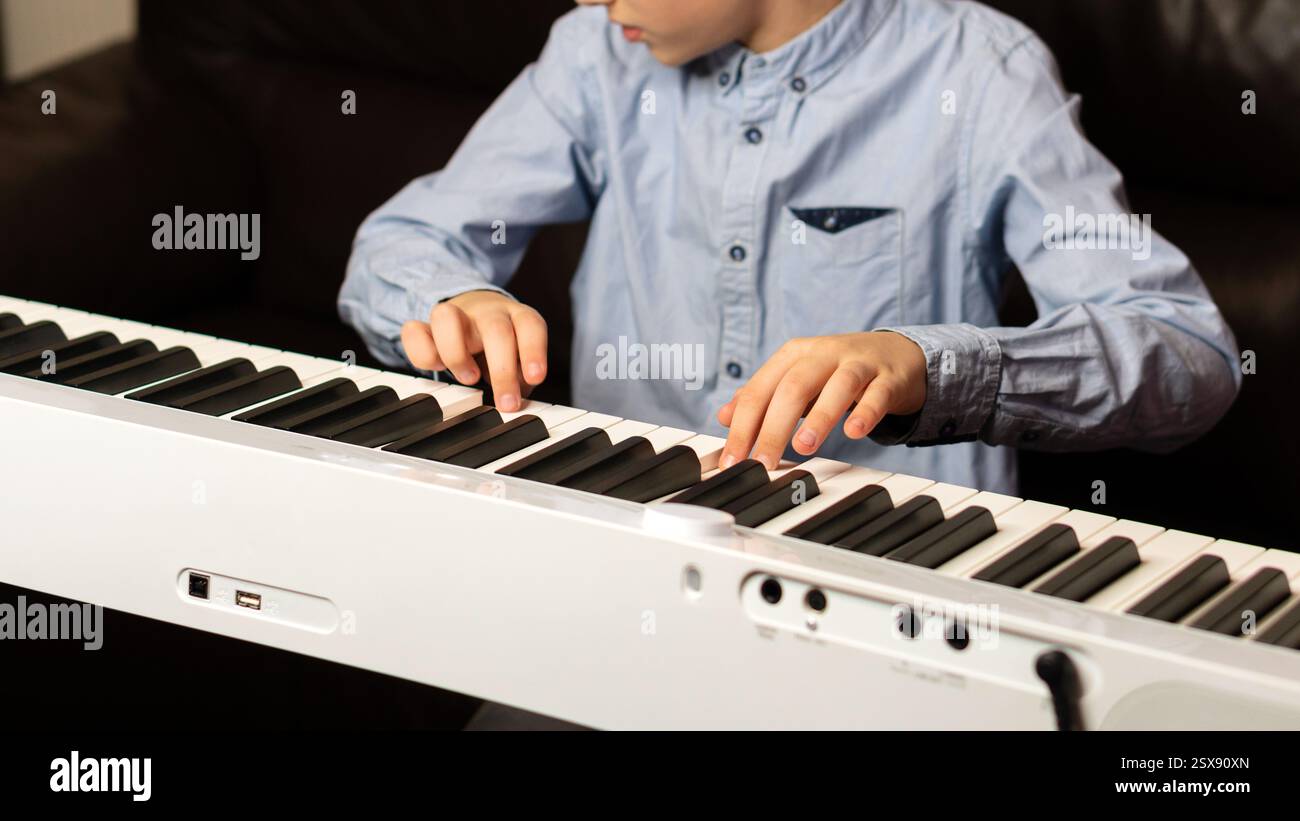 Child boy playing the keyboard with focused hands and fingers ...