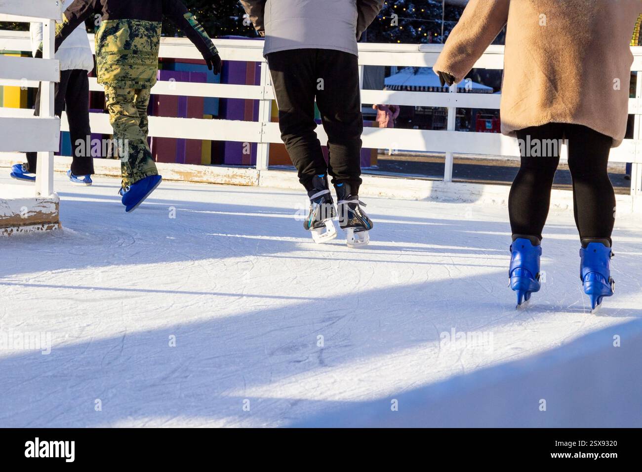 People are skating on a rink. The rink is surrounded by a white fence ...