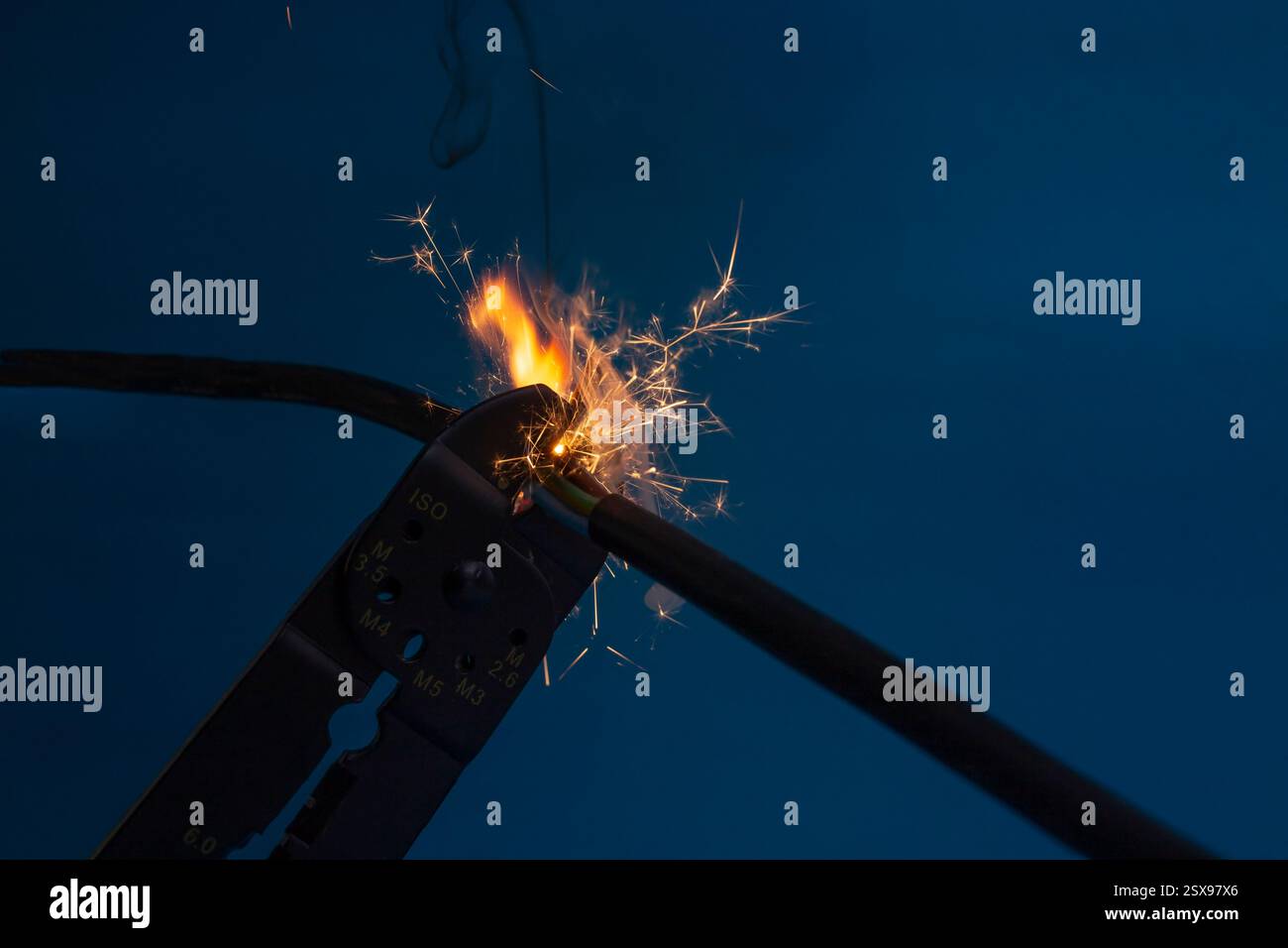 flame and sparks with wire stripper cutting electrical cables, on dark ...