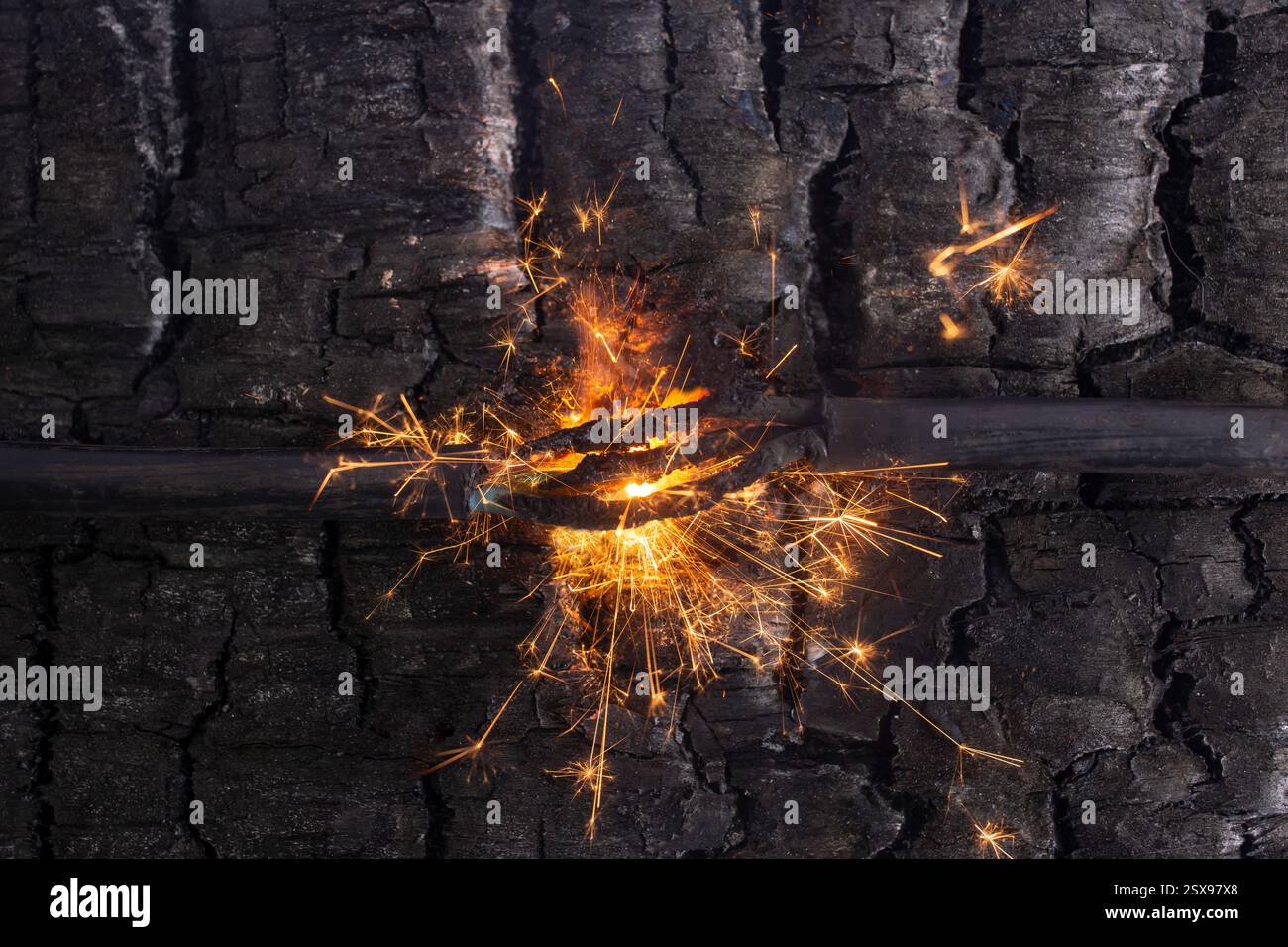 Sparks explosion between electrical cables, on burned wood texture ...
