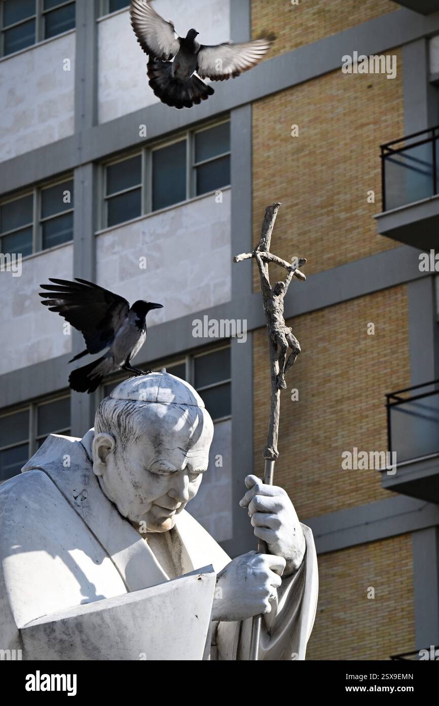 People pray near the statue of John Paul II outside the Gemelli ...