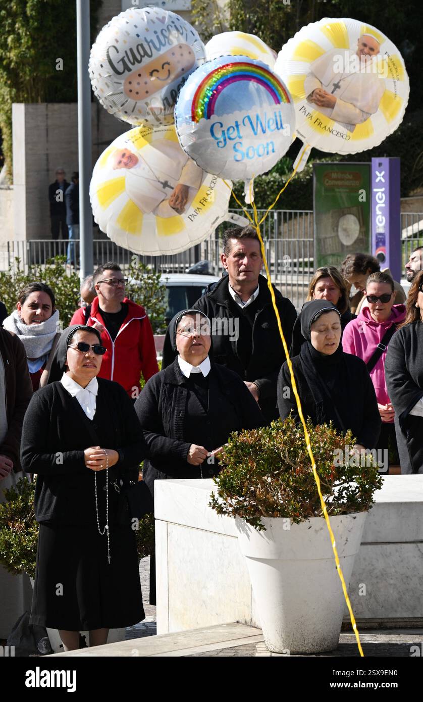 People pray near the statue of John Paul II outside the Gemelli ...