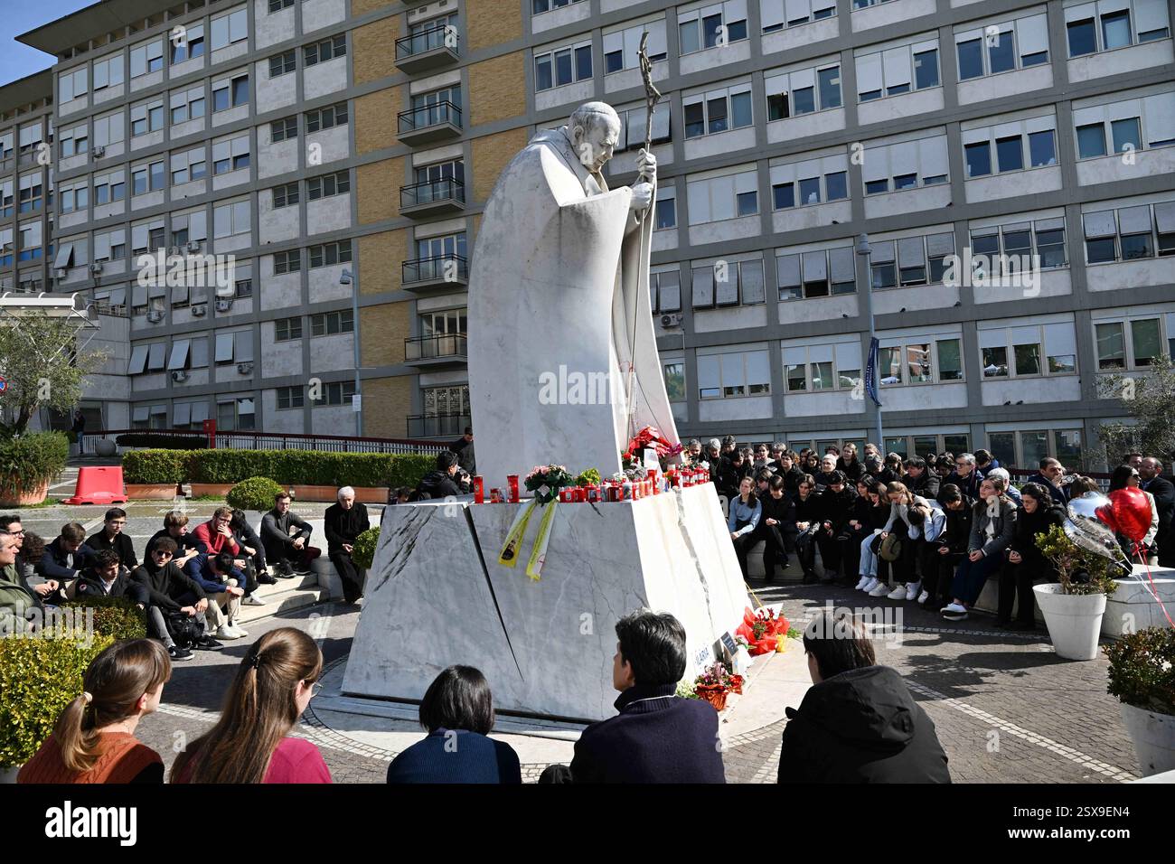 People pray near the statue of John Paul II outside the Gemelli ...