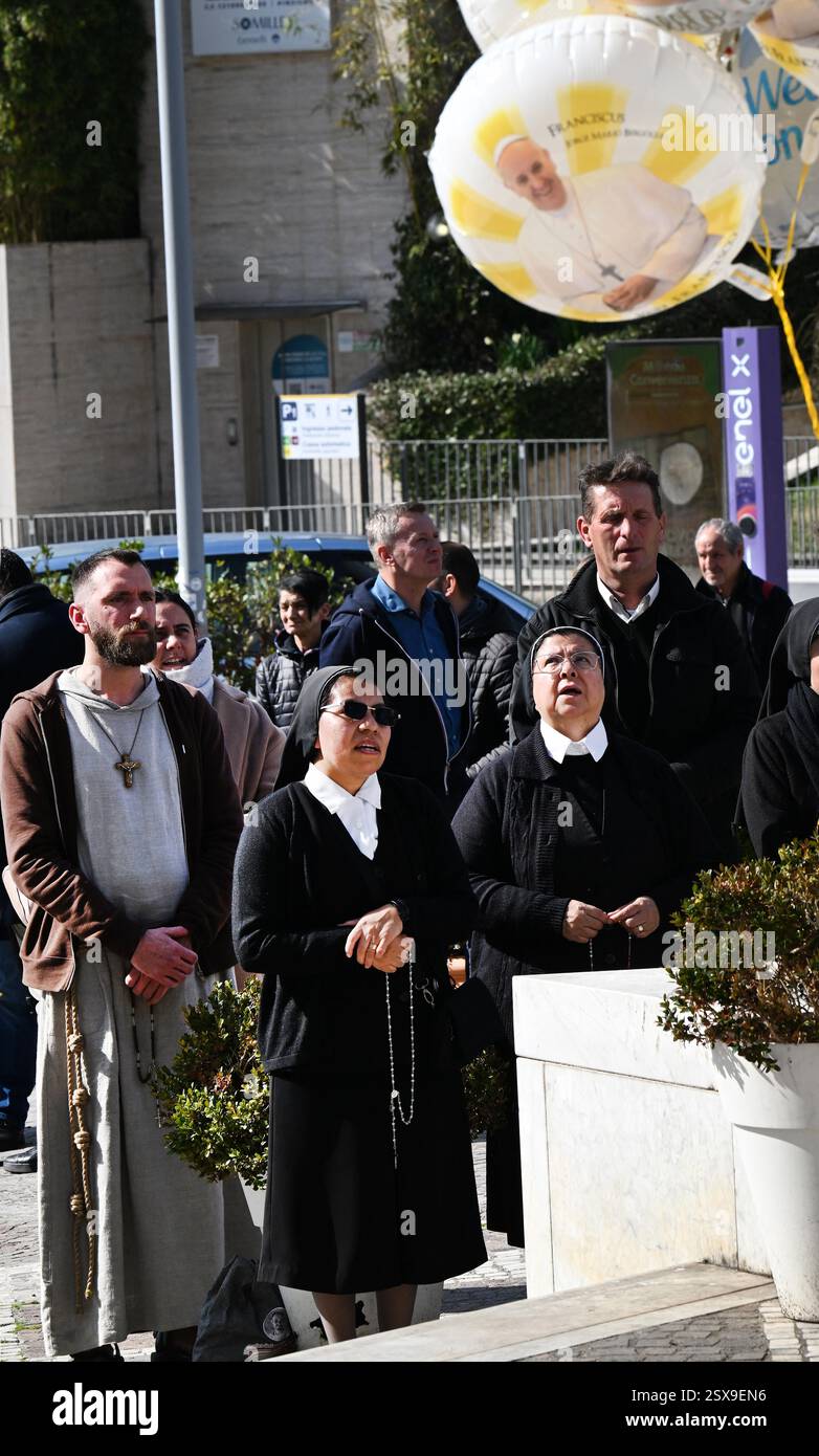People pray near the statue of John Paul II outside the Gemelli ...