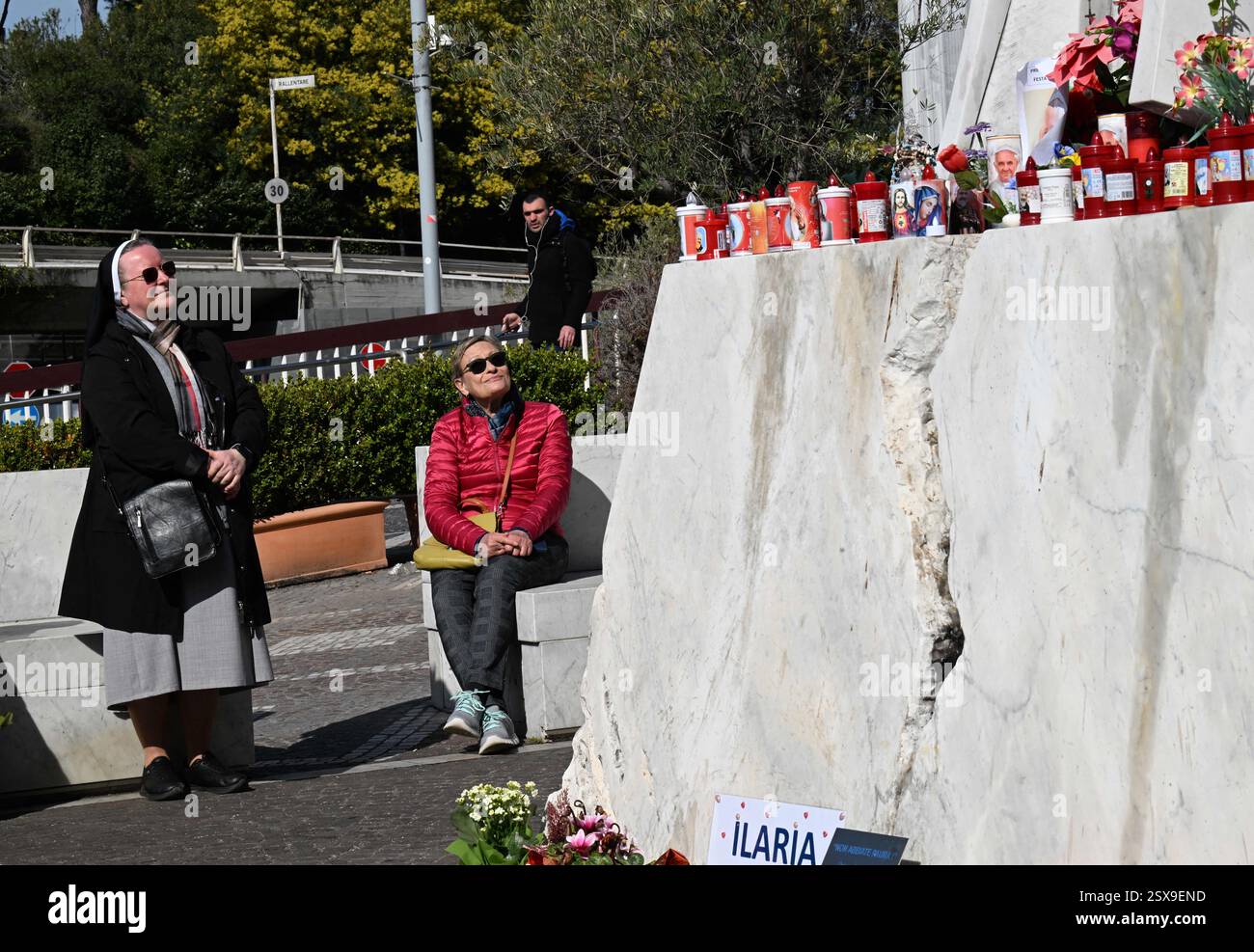 People pray near the statue of John Paul II outside the Gemelli ...