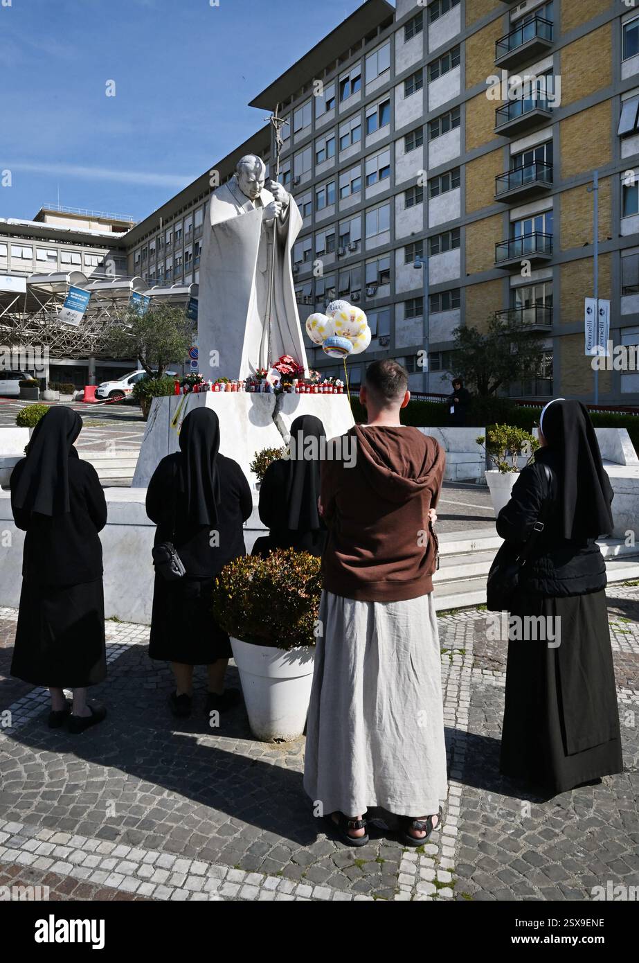 People pray near the statue of John Paul II outside the Gemelli ...