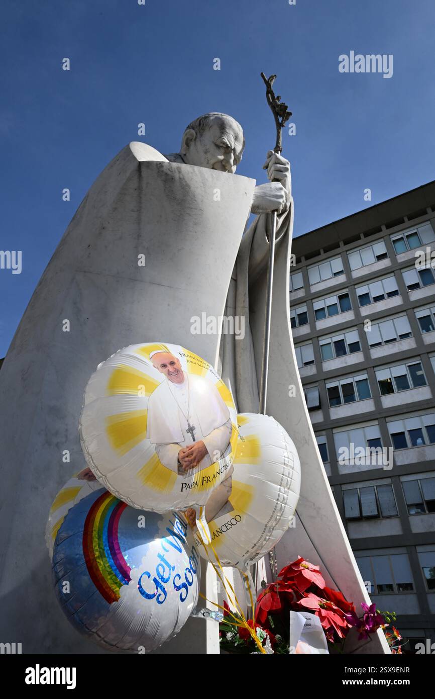 People pray near the statue of John Paul II outside the Gemelli ...