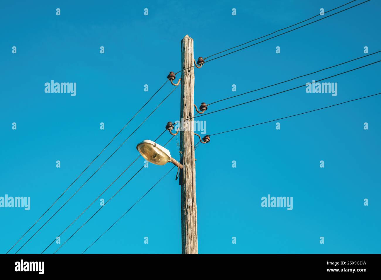 Old wooden lamp post with street light and electrical wires, selective ...
