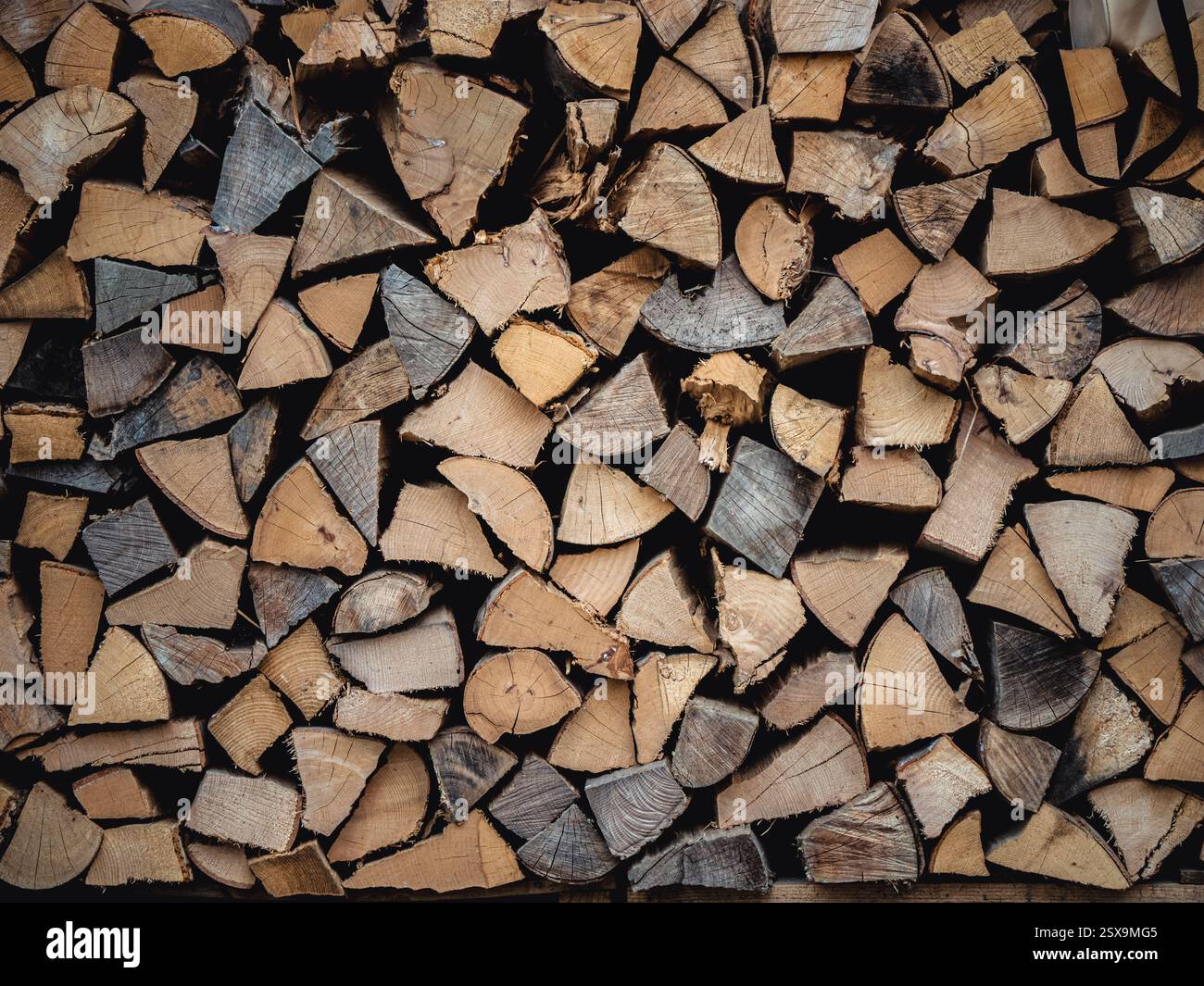 A neatly stacked pile of firewood logs with rough, textured surfaces ...