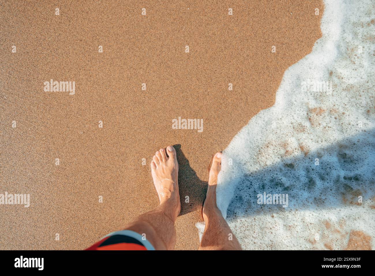 First person point of view of wet feet on sandy beach during summer ...