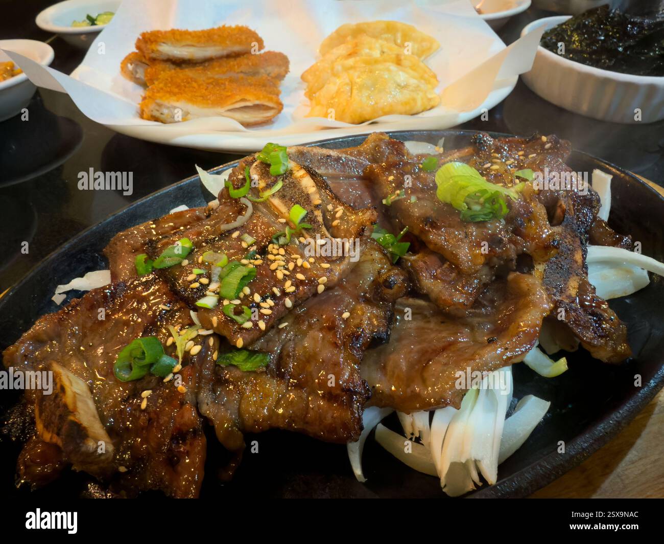 Close up of crispy BBQ thin slice beef on bone with side dishes in ...