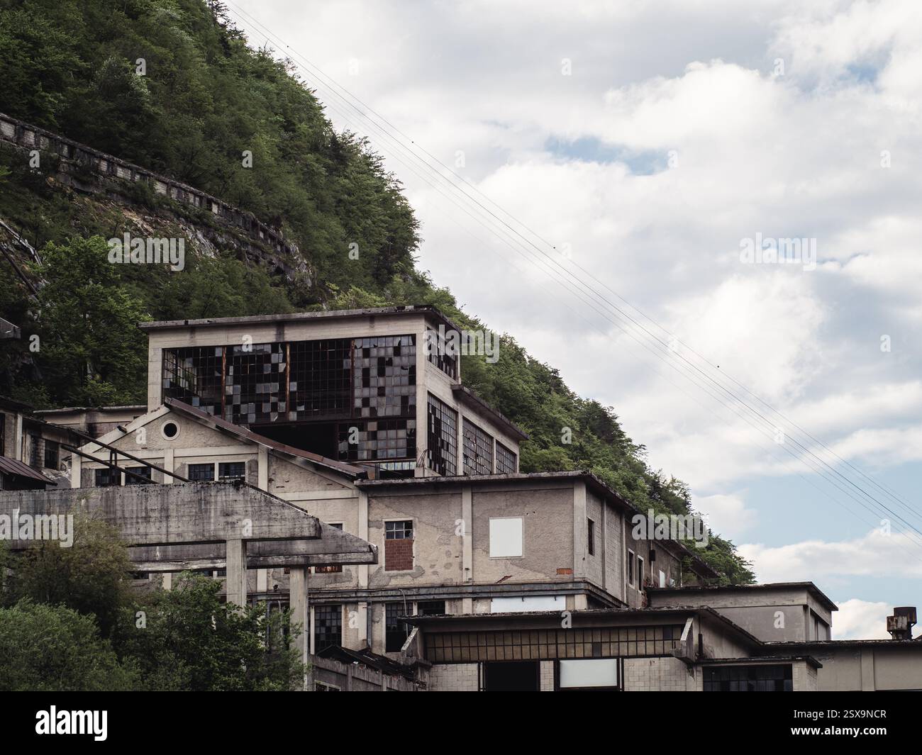 An old, abandoned mine with crumbling concrete buildings and rusting ...