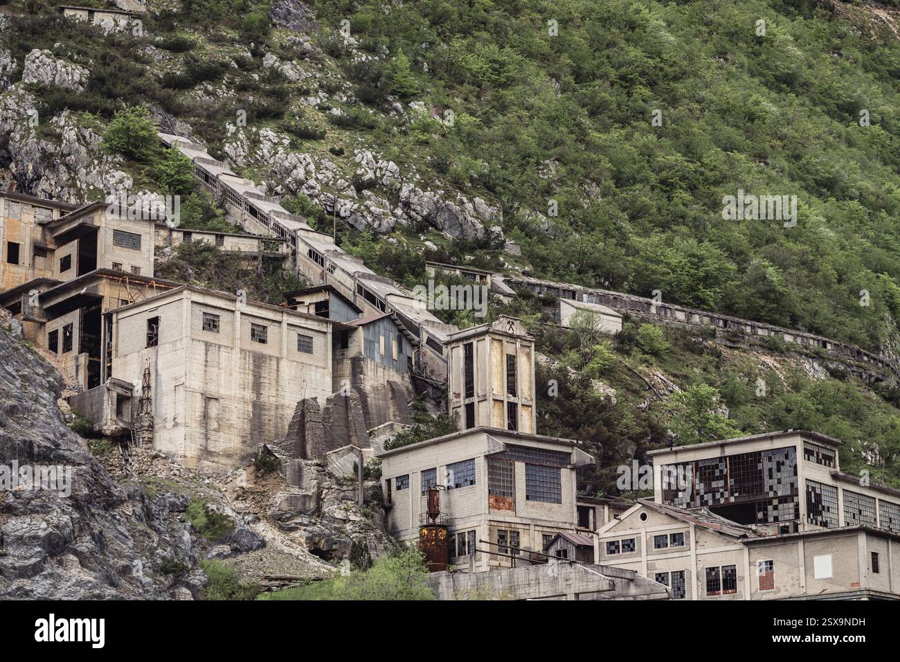 An old, abandoned mine with crumbling concrete buildings and rusting ...