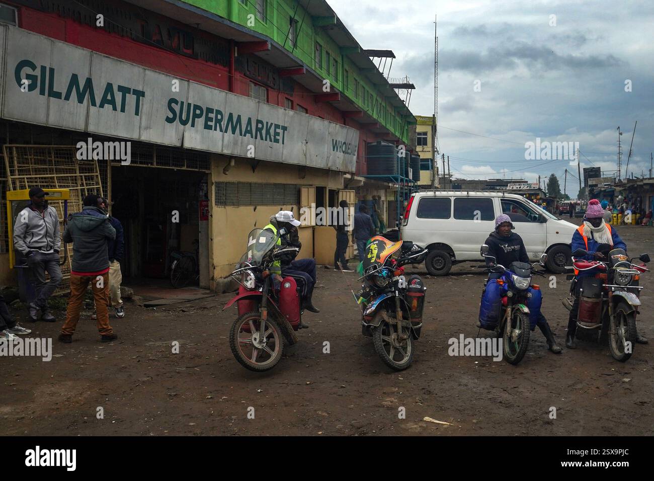Daily life in Gilgil, Kenya Men rest on parked motorcycles outside ...